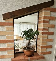Uma planta em vaso no peitoril da janela, com vista para uma sala de jantar.