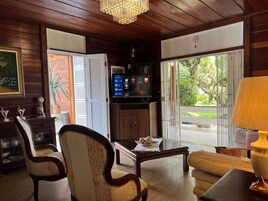 Quarto acolhedor com paredes de madeira, televisão, mesa de jantar e vista para o exterior.