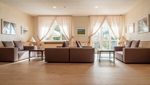 Uma sala de estar espaçosa com dois sofás, uma mesa de centro e uma janela grande com cortinas.
