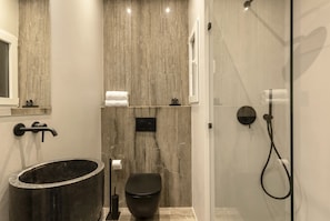 Um banheiro moderno com uma banheira preta grande, vaso sanitário e chuveiro com divisória de vidro.