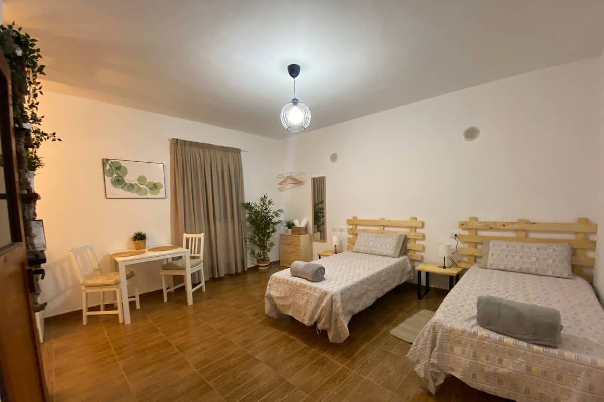 Quarto com duas camas, uma escrivaninha e uma cadeira.