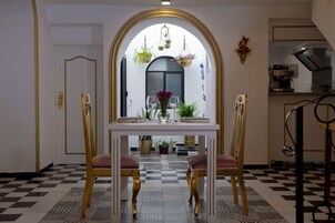 Uma área de refeições com uma mesa branca, duas cadeiras e piso xadrez.