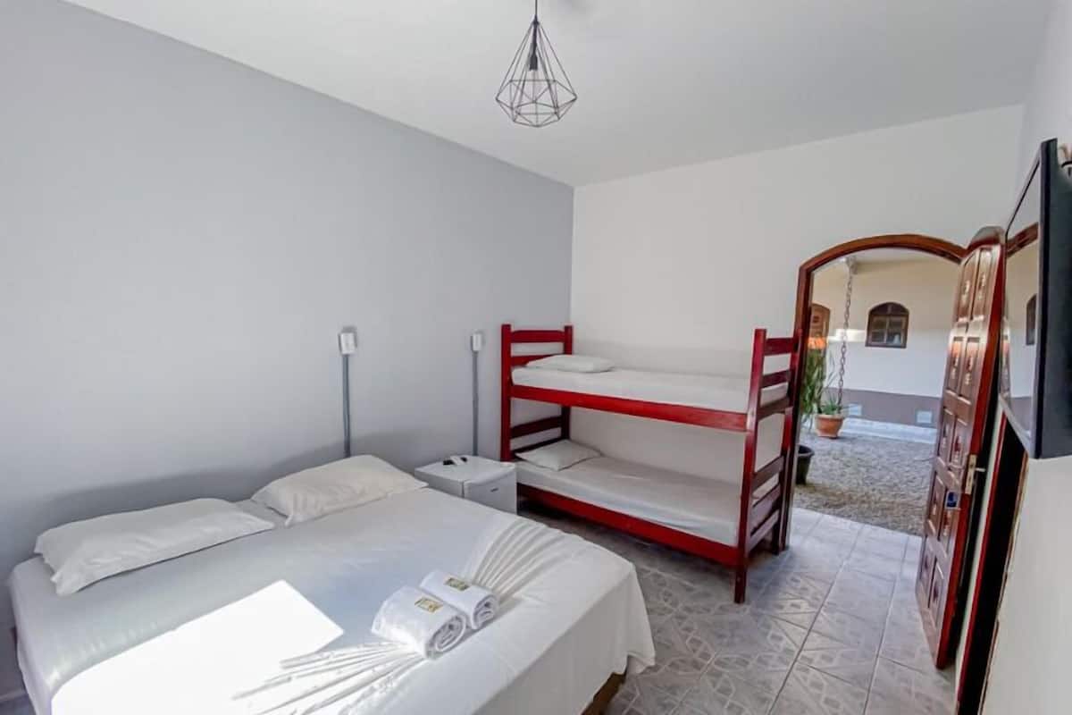 Um quarto com uma cama de solteiro, uma cama individual e uma pequena mesa de cabeceira.