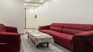 Uma sala de estar moderna com um sofá vermelho, uma mesa de jantar com pratos e copos, e um ventilador de teto.