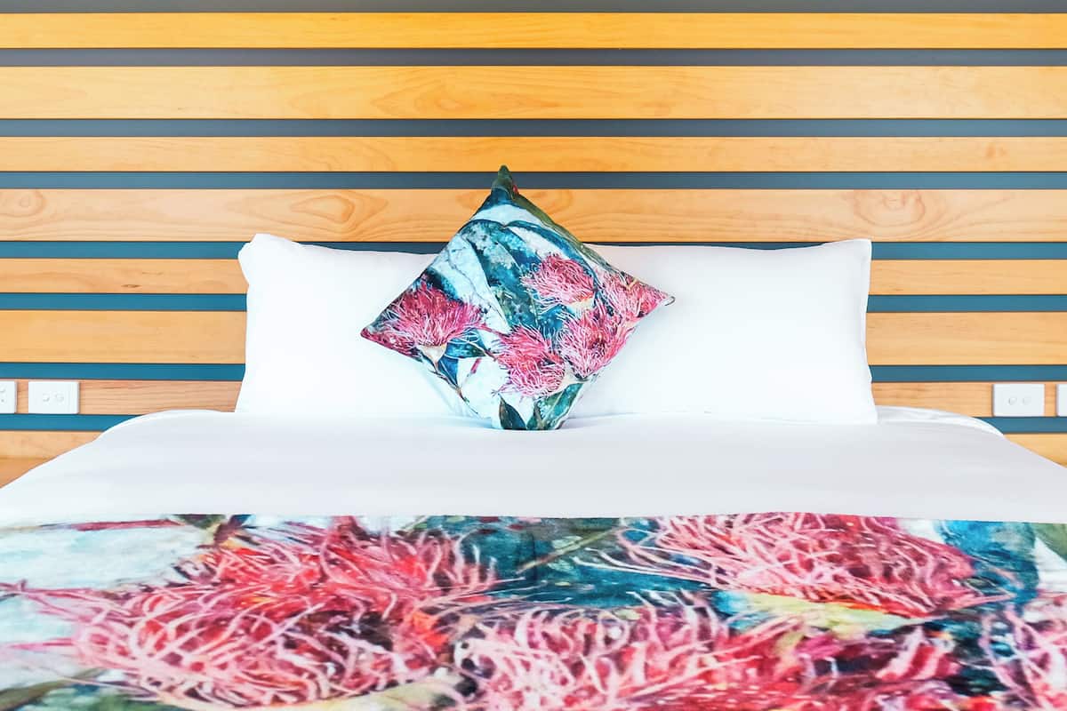 Cama com travesseiro estampado em flor e colcha de design semelhante.