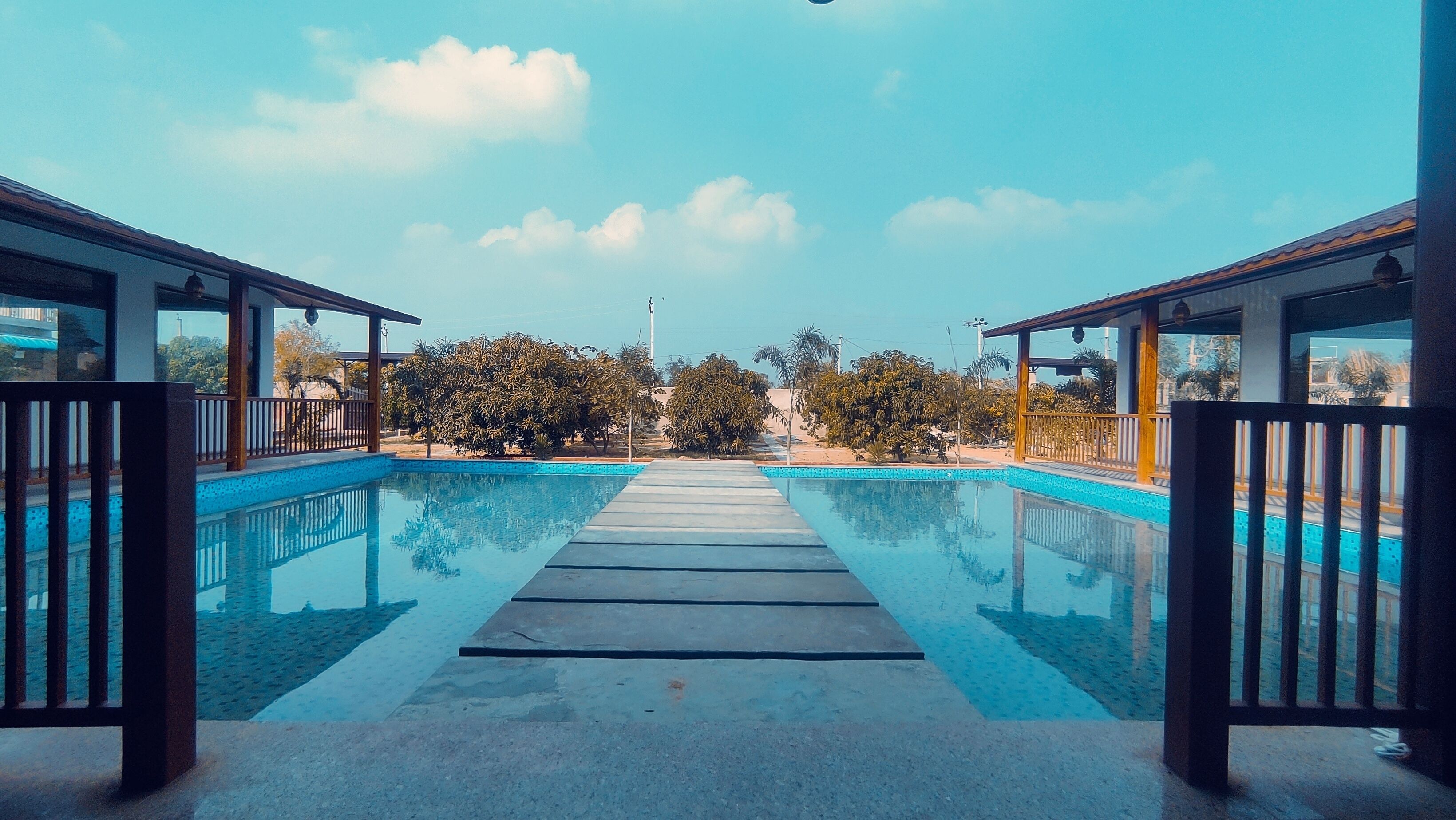 Piscina com vista clara do céu e árvores ao fundo.
