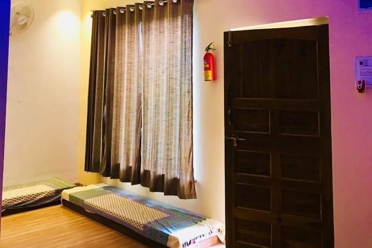 Quarto com cama, porta e teto com iluminação embutida.
