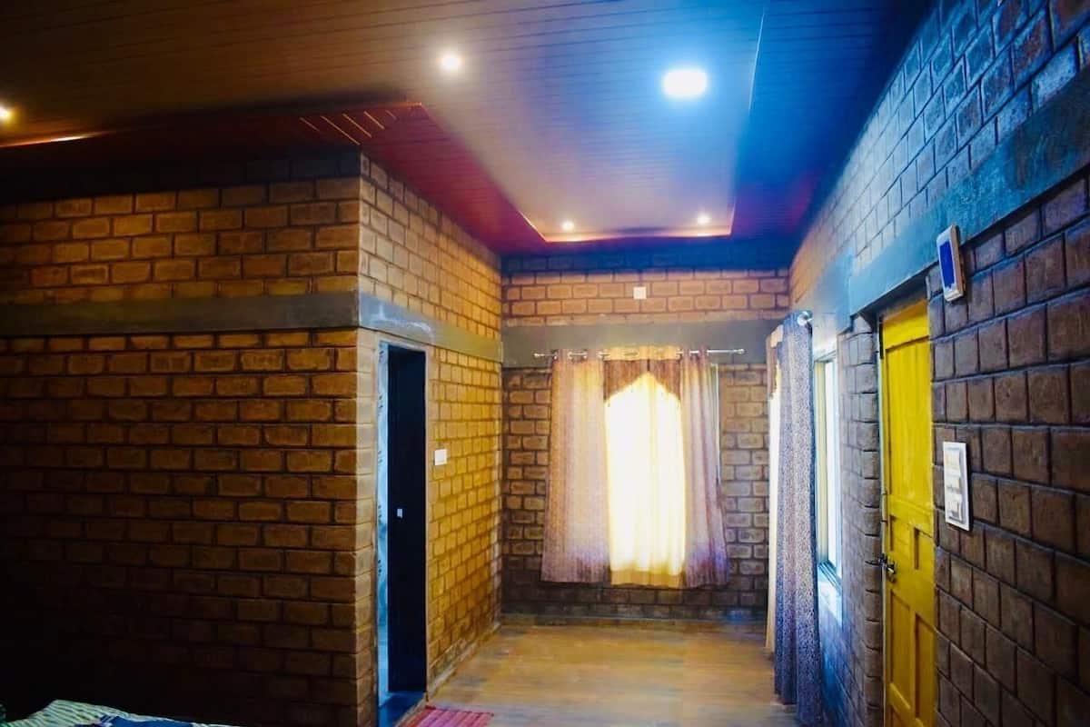 Um corredor estreito com paredes de tijolo, uma porta à esquerda e uma porta amarela à direita.