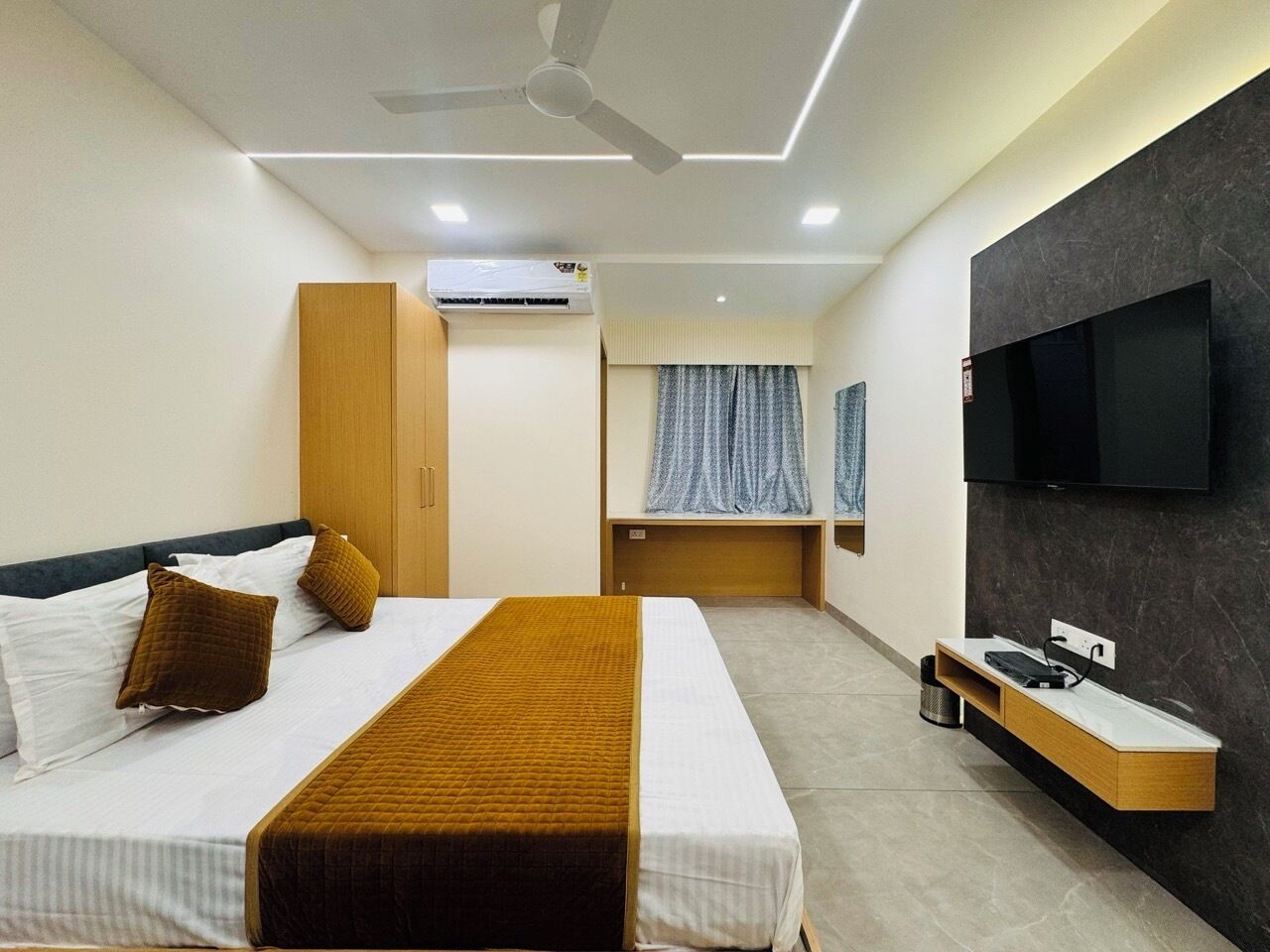 Quarto de hotel moderno com cama, televisão, guarda-roupa e ar condicionado.