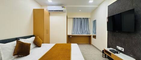Quarto de hotel moderno com cama, televisão, guarda-roupa e ar condicionado.