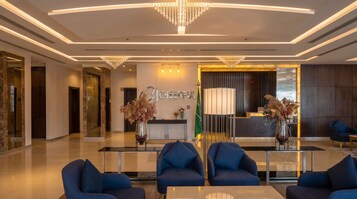 Um lobby moderno com balcão de recepção, assentos azuis e um candelabro.