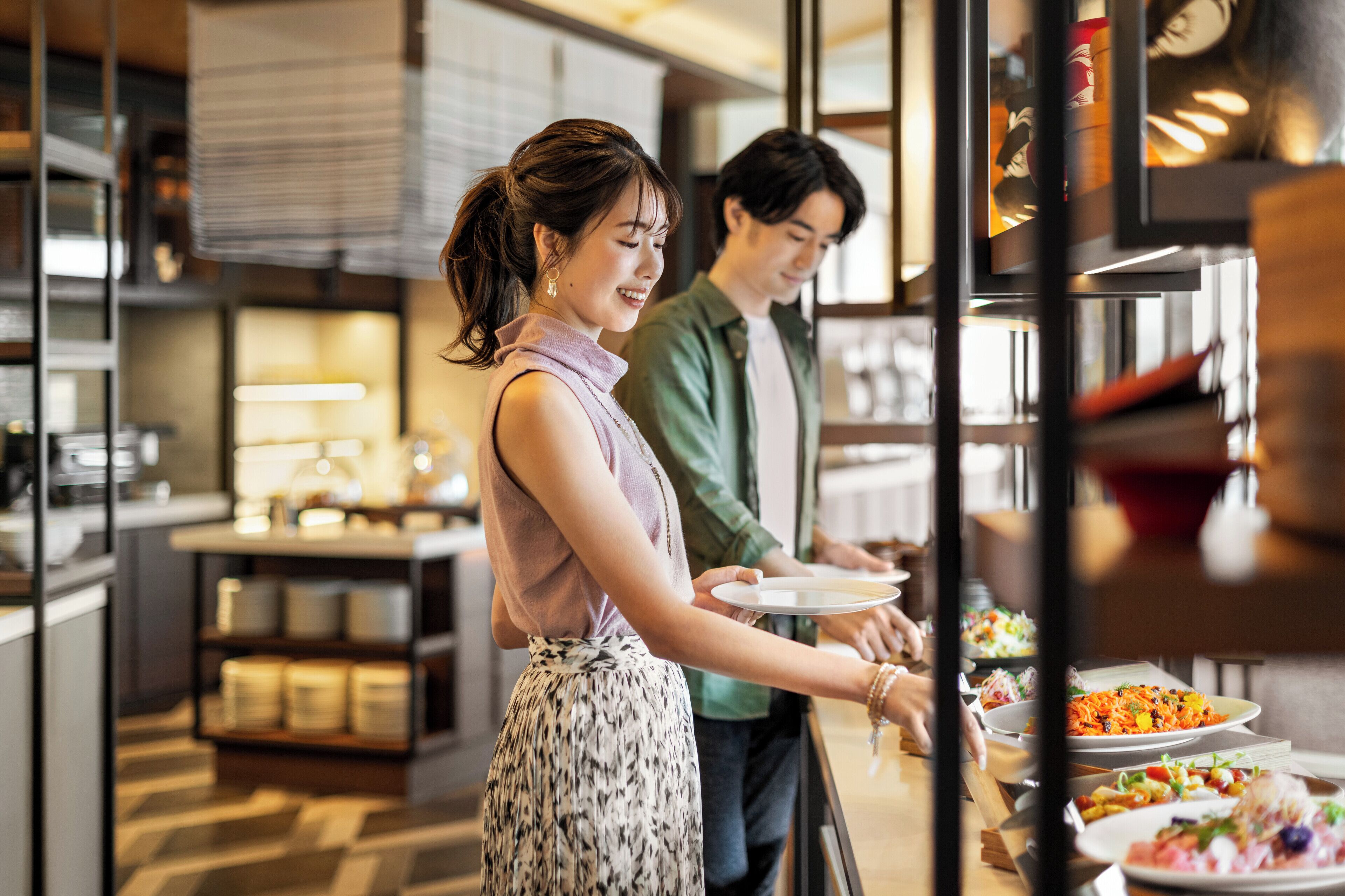 Uma área de buffet com diversos pratos e uma pessoa servindo.