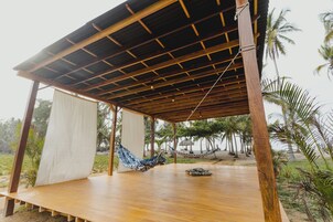 Um deck de madeira com uma rede e uma estrutura coberta de palha.