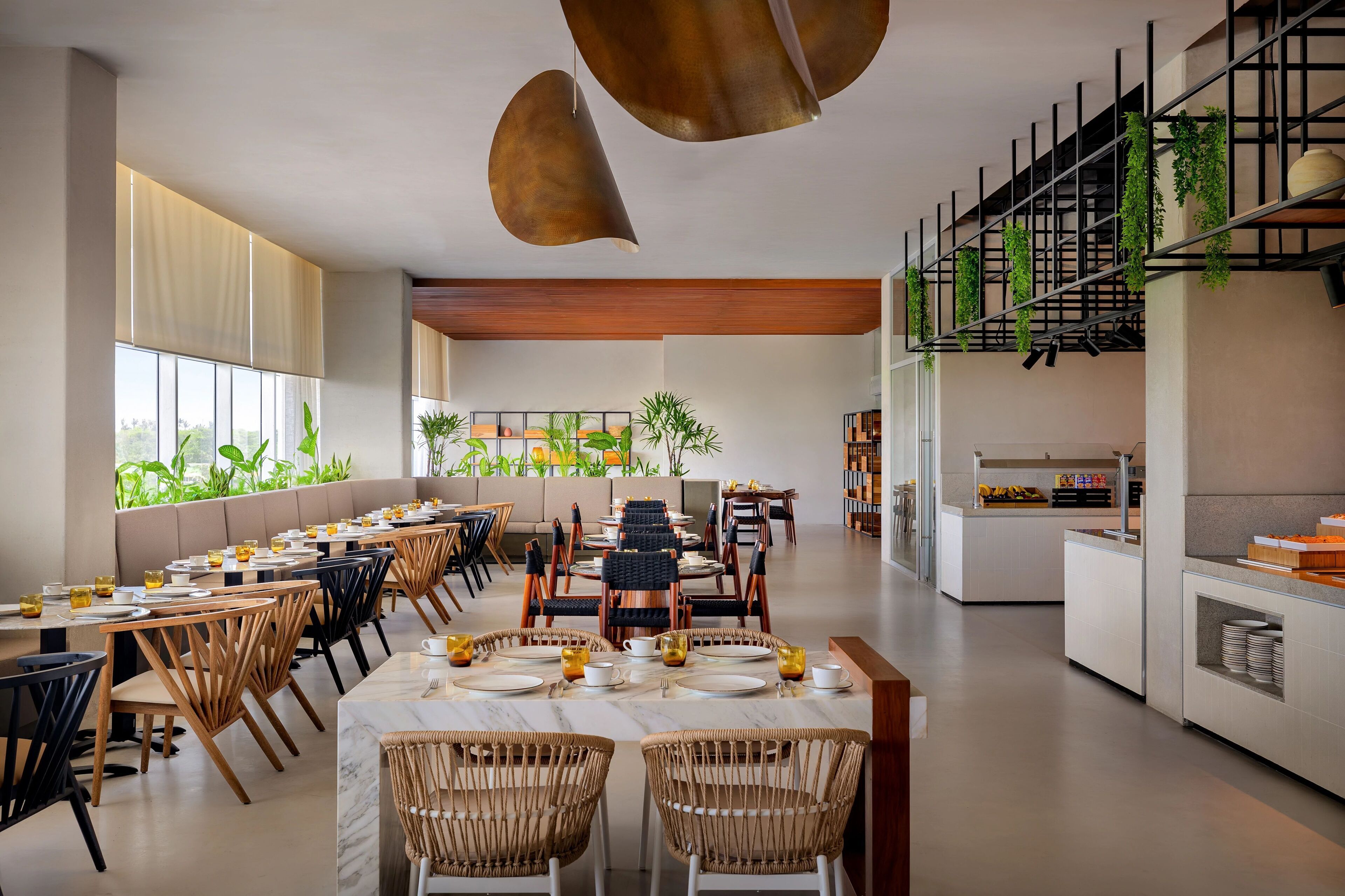 Uma área de refeições moderna com mesas grandes, cadeiras e um buffet.