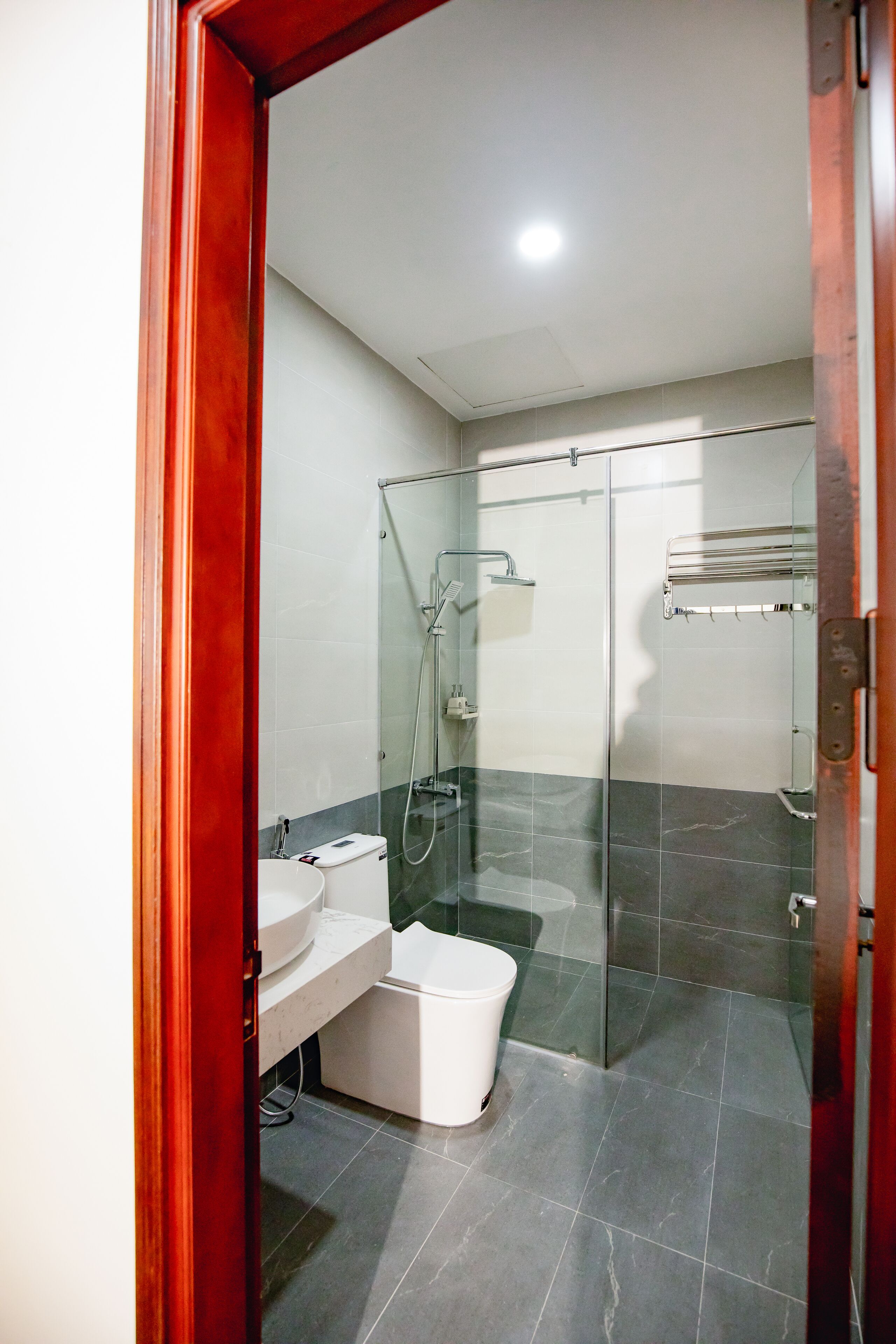 Uma casa de banho moderna com cabine de duche em vidro, lavatório branco e sanita.