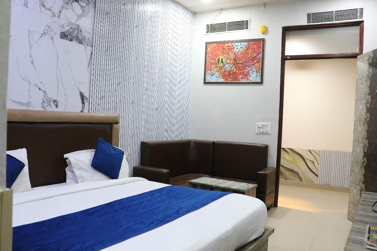 Quarto de hotel com uma cama, um sofá marrom, uma mesinha e um quadro na parede.