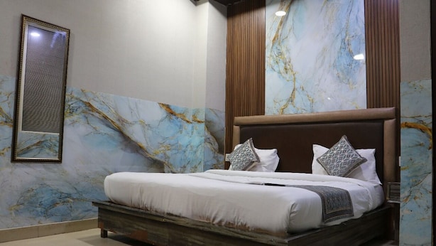 Quarto com parede estampada em mármore, estrutura de cama em madeira e cabeceira com almofadas decorativas.