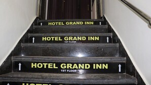 Uma escadaria com placas indicando 'HOTEL GRAND INN' e '1º ANDAR'.