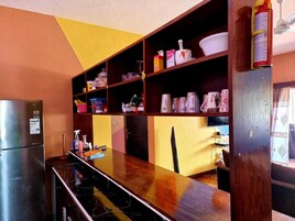 Uma cozinha com geladeira, prateleiras de madeira e bancada de mármore.