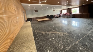 Um salão amplo com piso de mármore polido, paredes de painéis de madeira e ventiladores de teto.