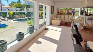 Uma sala de estar moderna com uma grande janela, piscina e área de cozinha.