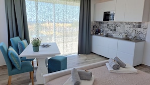 Uma cozinha moderna com armários brancos, painel de fundo decorado e uma área de refeições com mesa e cadeiras.