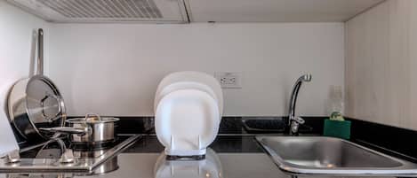 Uma cozinha compacta com micro-ondas, cafeteira e forno embutido.