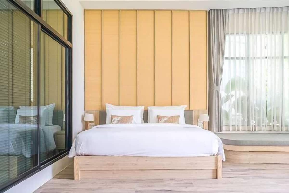 Quarto com cama grande, janela com cortinas e vista para o exterior.