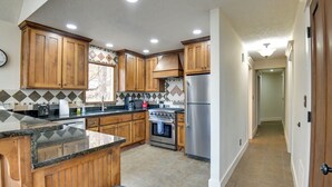 Uma cozinha com armários de madeira, bancada de granito, eletrodomésticos de aço inoxidável e backsplash com ladrilhos estampados.