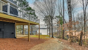 Uma casa com varanda coberta, vista para um lago e área arborizada.
