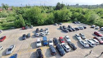 Um parque de estacionamento com vários carros e algumas pessoas a caminhar.