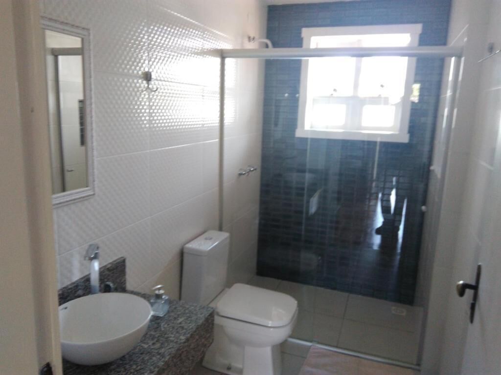 Casa de banho com lavatório branco, sanita e cabine de duche.