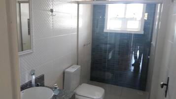 Casa de banho com lavatório branco, sanita e cabine de duche.
