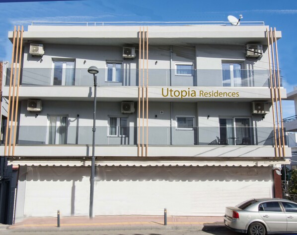 Um edifício com vários andares, varandas, aparelhos de ar condicionado e um carro estacionado na frente.