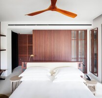 Quarto moderno com uma cama grande, cabeceira de madeira, mesas de cabeceira e ventilador de teto.