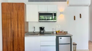 Uma cozinha moderna com armários brancos, geladeira de aço inoxidável, micro-ondas e cafeteira.