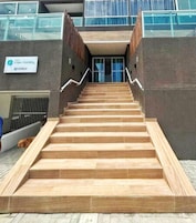 Escadas de madeira conduzem à entrada de um edifício, com uma placa acima que diz 'Cúpico Gardenia'.