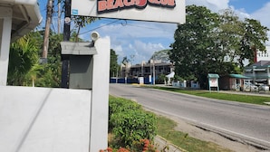 Placa do Negri Beach Club com vista clara da área circundante, incluindo uma estrada, vegetação e um edifício ao fundo.
