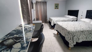 Quarto com duas camas, uma escrivaninha e uma cadeira.