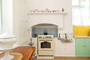 Uma cozinha com fogão branco, painel de azulejos azul estampado e armário verde.