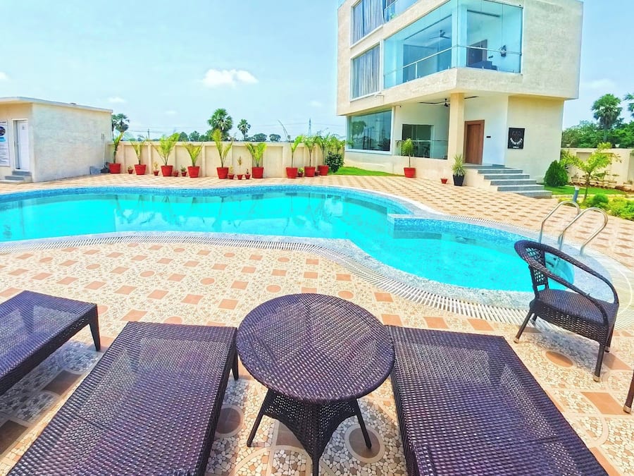 Área de piscina com espreguiçadeiras e um edifício moderno ao fundo.