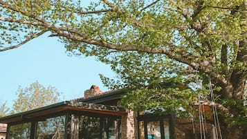 Um edifício rústico de pedra com estrutura de vidro, rodeado por árvores e céu claro.