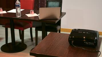 Uma sala de conferências com um laptop, um projetor e uma garrafa de água sobre a mesa.