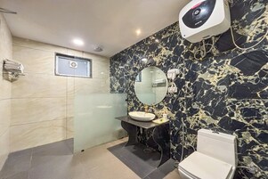 Um banheiro com parede de mármore, pia com espelho, vaso sanitário e secador de cabelo na parede.