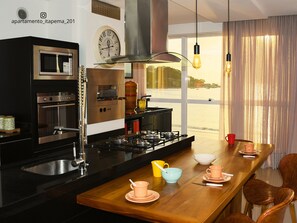 Apartamento Deluxe, vista para a praia | Cozinha privada | Um frigorífico, utensílios de cozinha, mesas de jantar 