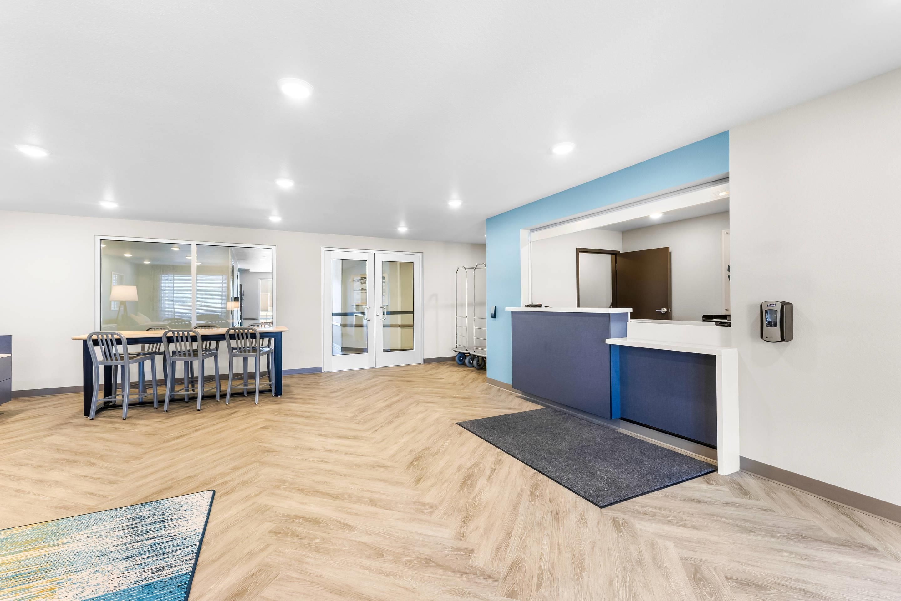 Uma área de recepção moderna com balcão, cadeiras e uma sala de espera com mesa e cadeiras.