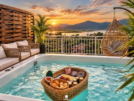Área de piscina no terraço com hidromassagem, cesta de vime com comidas e bebidas, cadeiras de descanso e vista para montanhas e pôr do sol.
