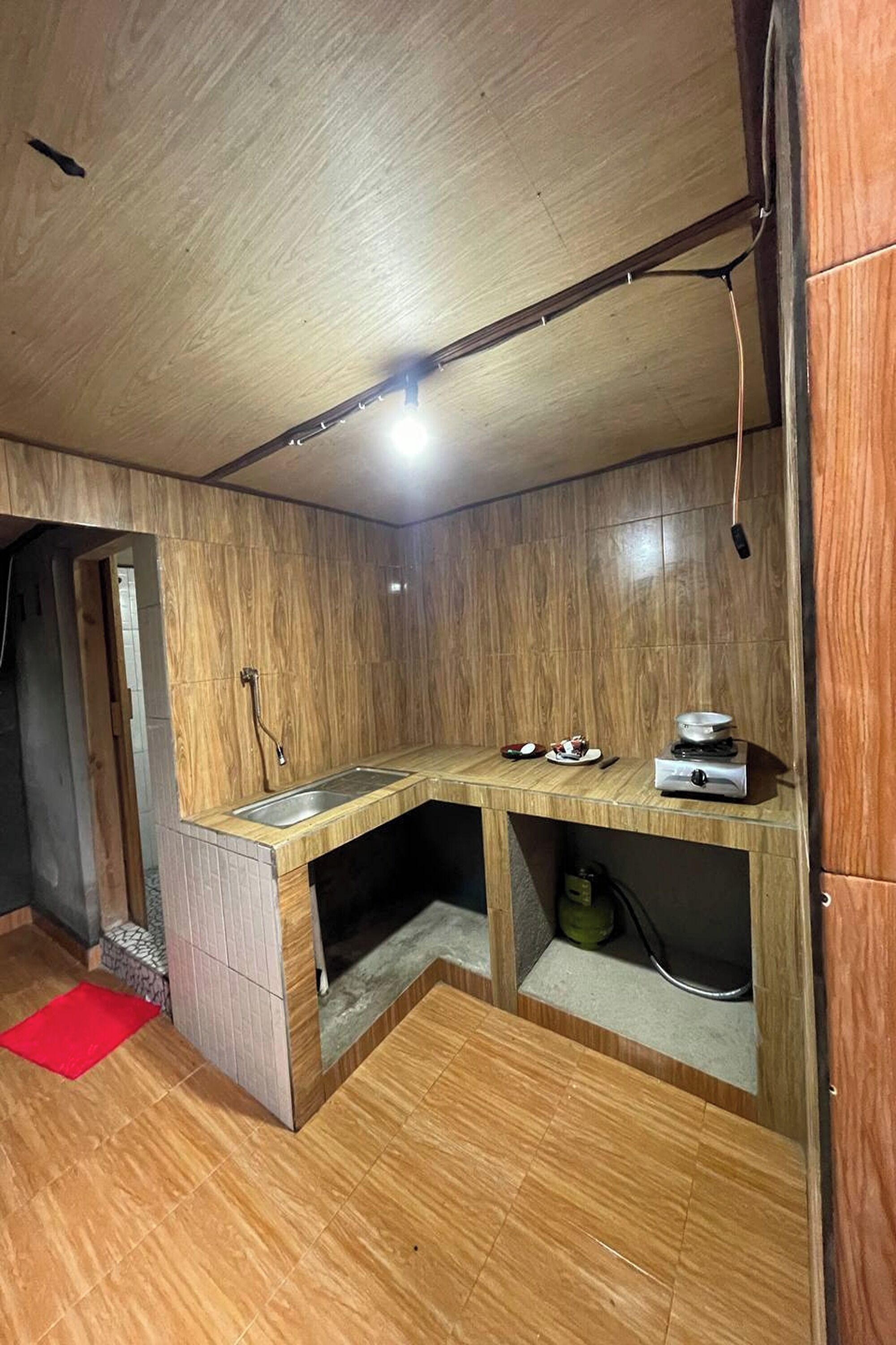 Uma cozinha compacta com bancada de madeira, pia e fogão a gás.