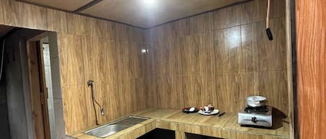 Uma cozinha compacta com bancada de madeira, pia e fogão a gás.