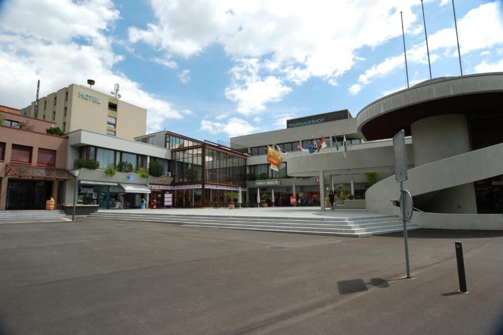 Um hotel moderno com fachada de vidro, um pátio central e estrutura de edifício curva.